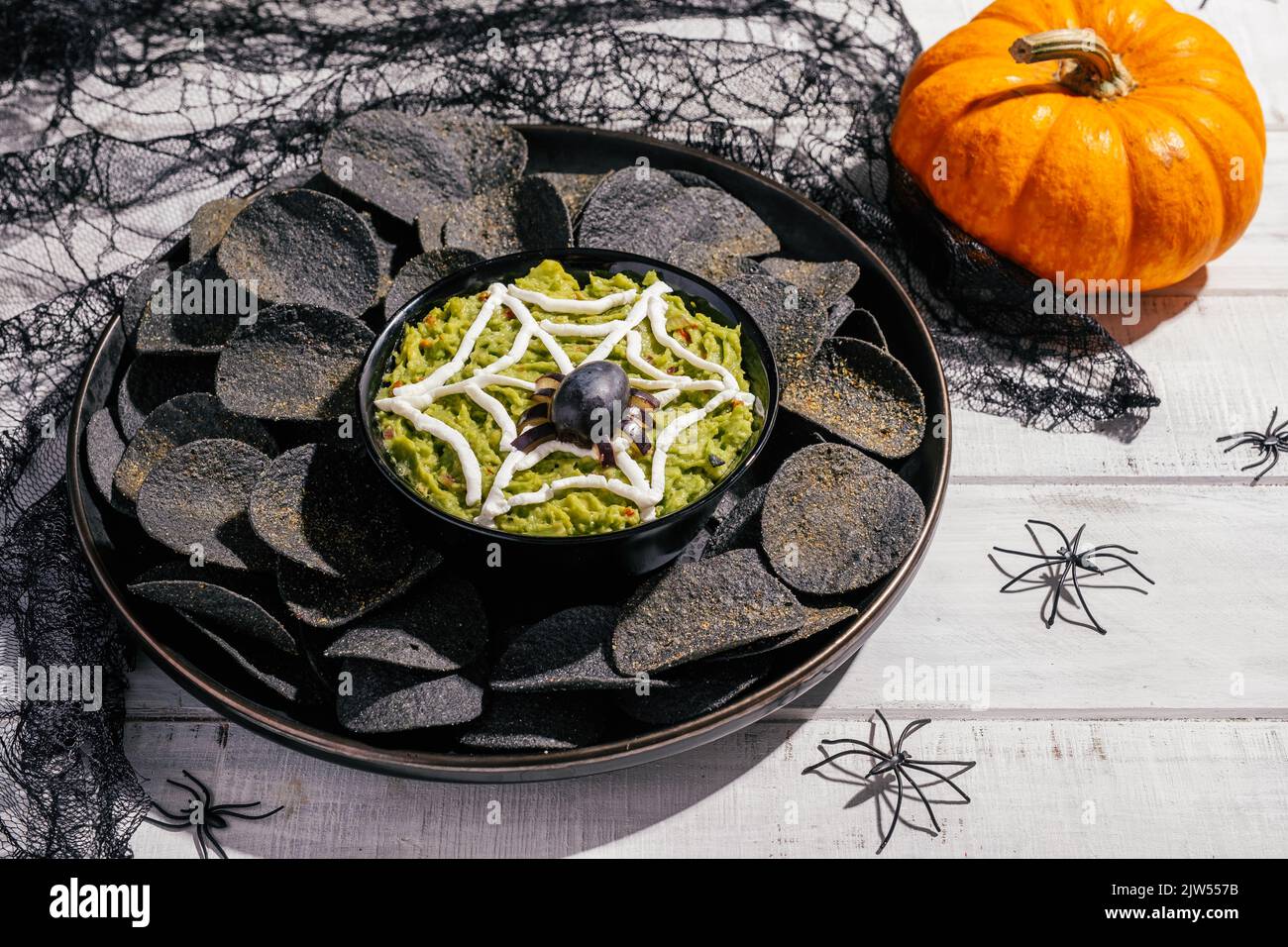 Spooky Halloween black potato chips with guacamole dip Stock Photo - Alamy