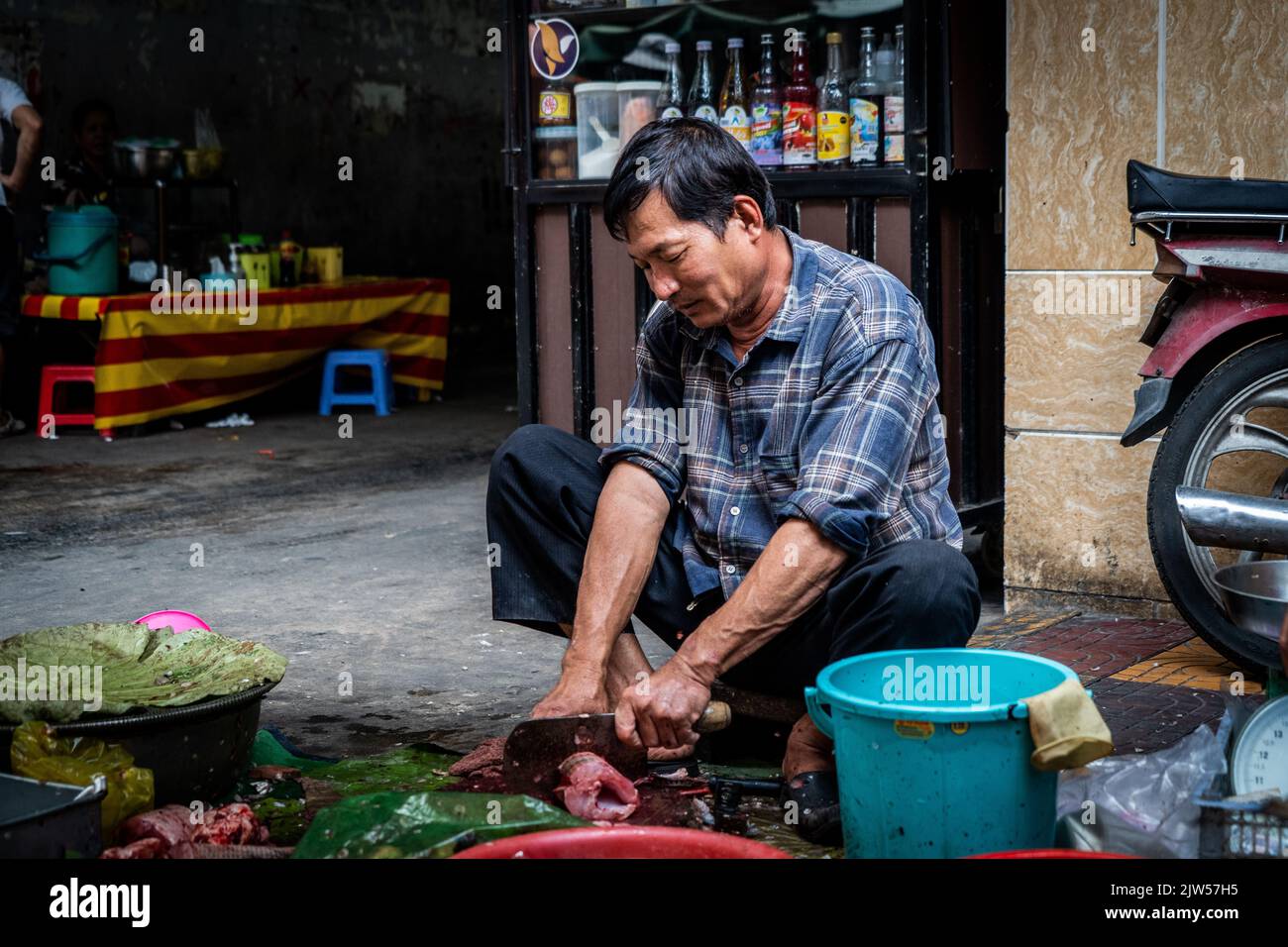 A street butcher chops meat at an outdoor wet market in Phnom Penh ...