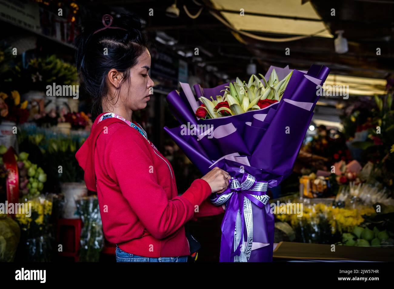 A street florist puts the finishing touches on a bouquet of roses at ...