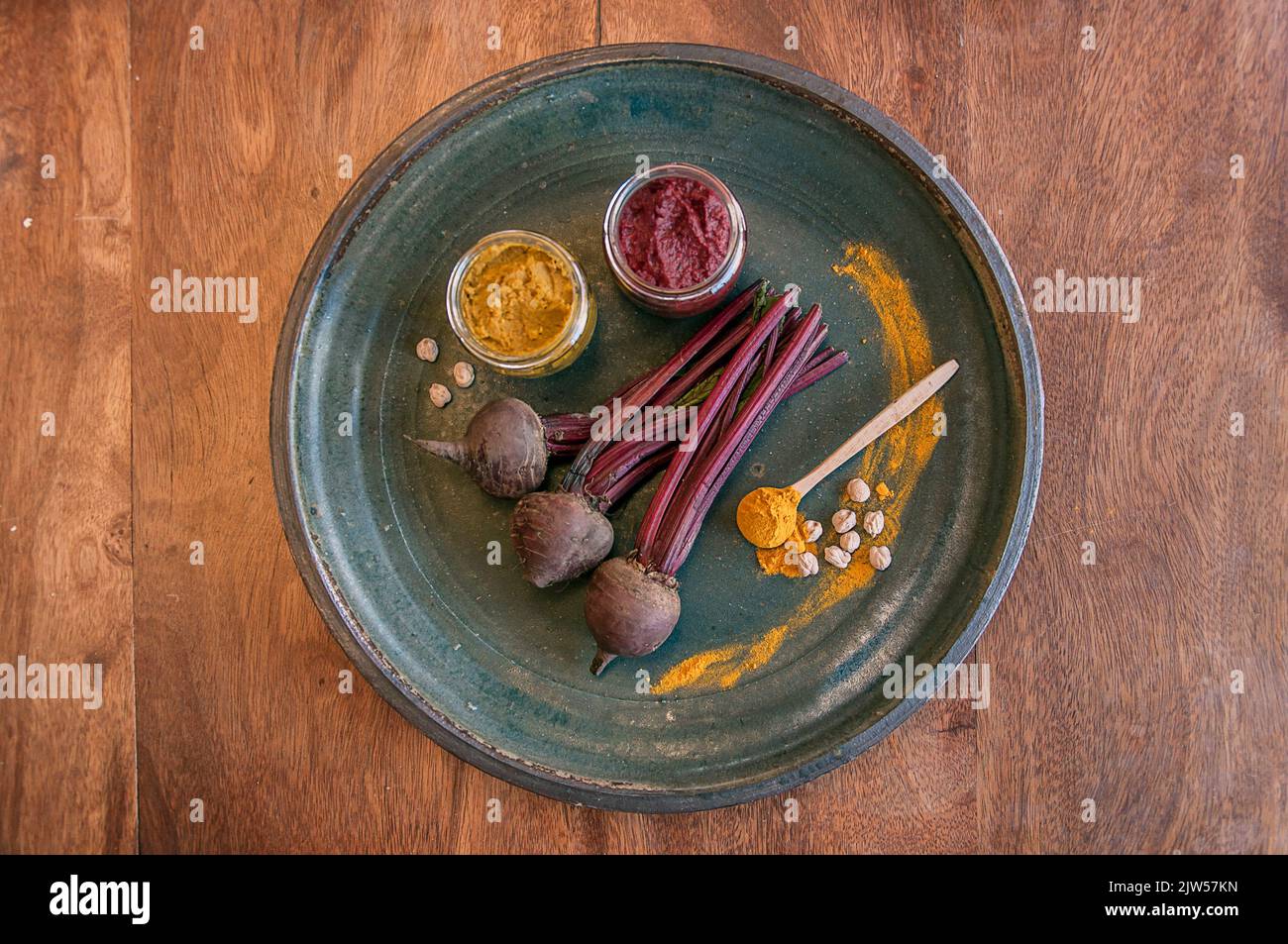 Turmeric and beet dip inside a jar and all the ingredients on a blue ...