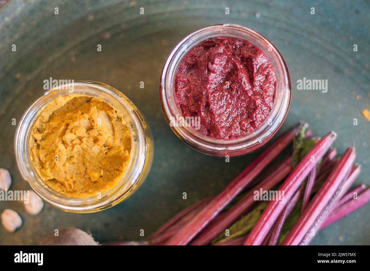 Turmeric and beet dip inside a jar and all the ingredients on a blue ...