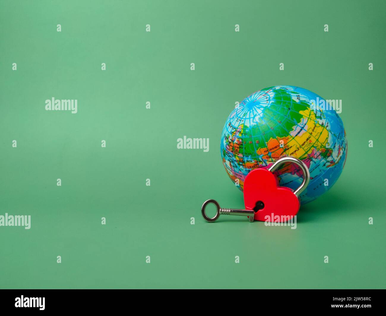 Heart-shaped red lock with key and earth globe on a green screen Stock ...