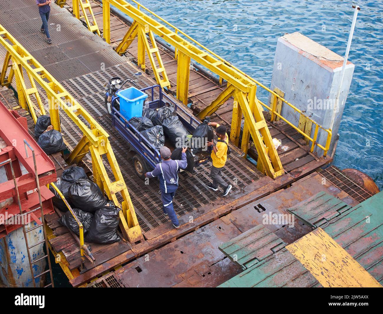 Two cleaners are picking up trash from the ferry using a small pickup ...