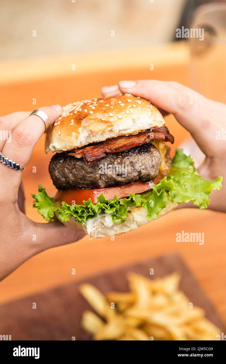 Hands holding a burger, on a restaurant table. Delicious and nutritious ...