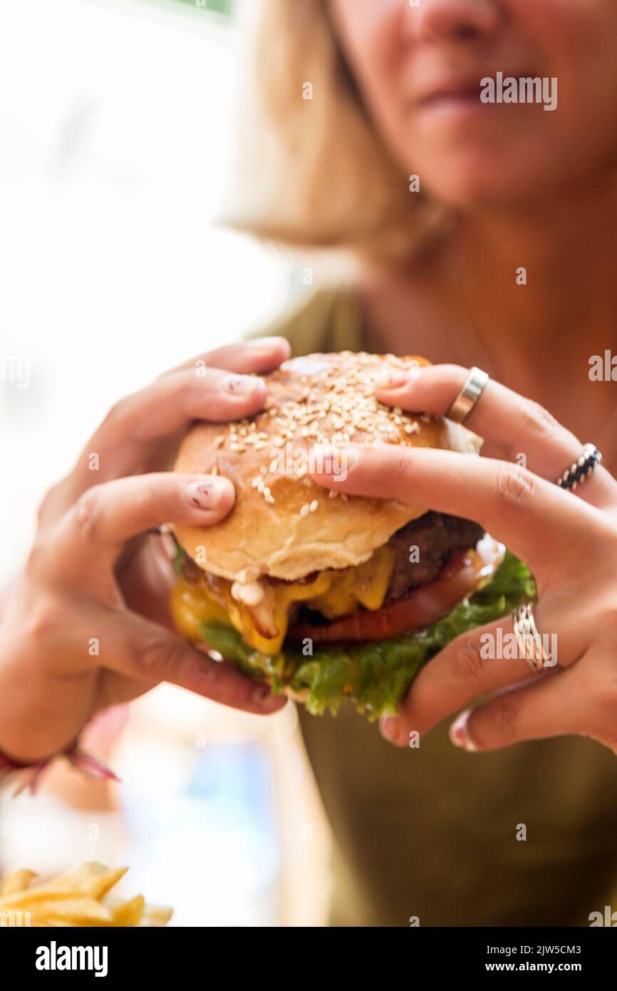 Hands holding a burger, on a restaurant table. Delicious and nutritious ...