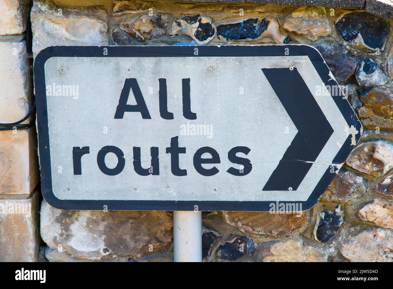 A closeup of a road sign "All routes" indicating the direction of the ...