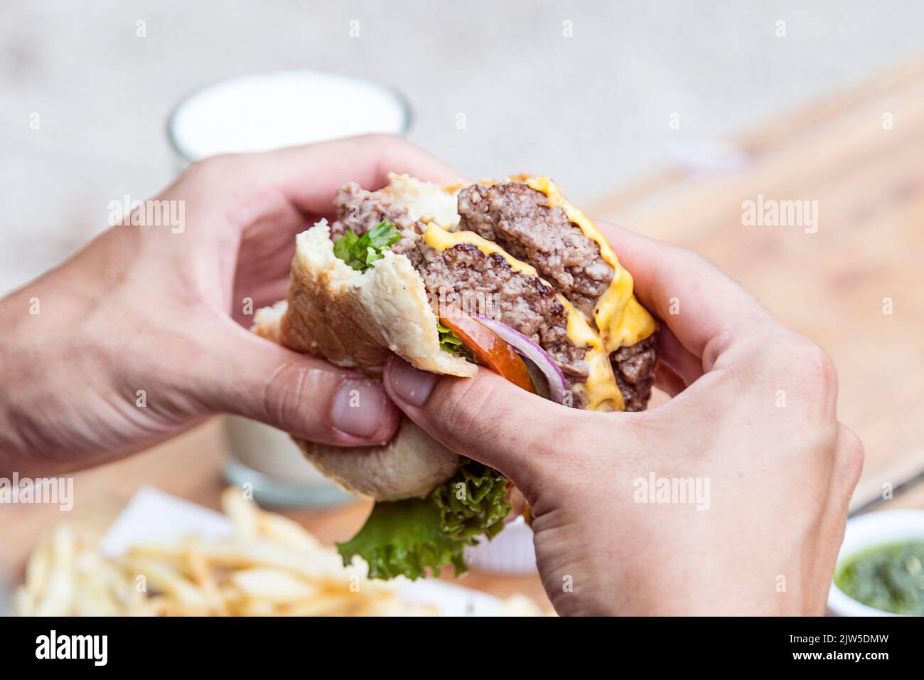Hands holding a burger, on a restaurant table. Delicious and nutritious ...