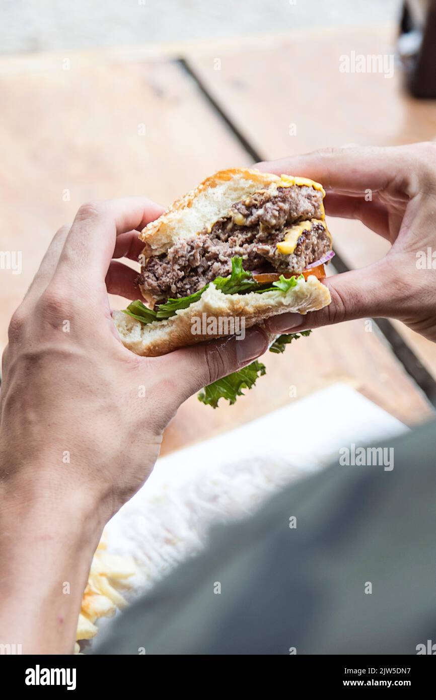 Hands holding a burger, on a restaurant table. Delicious and nutritious ...