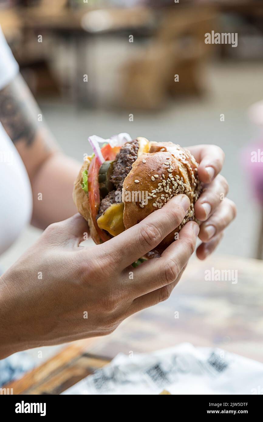 Hands holding a burger, on a restaurant table. Delicious and nutritious ...