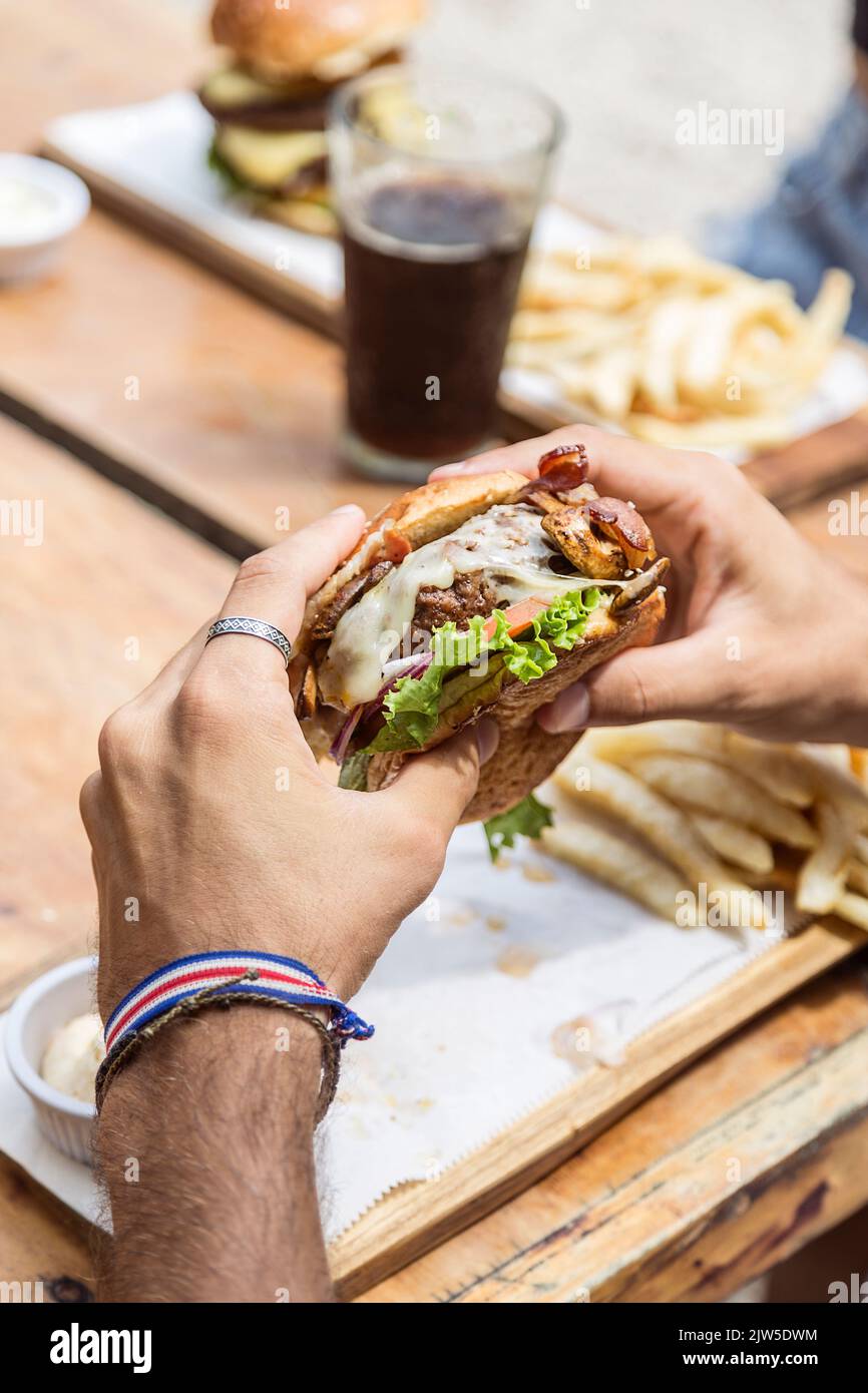 Hands holding a burger, on a restaurant table. Delicious and nutritious ...