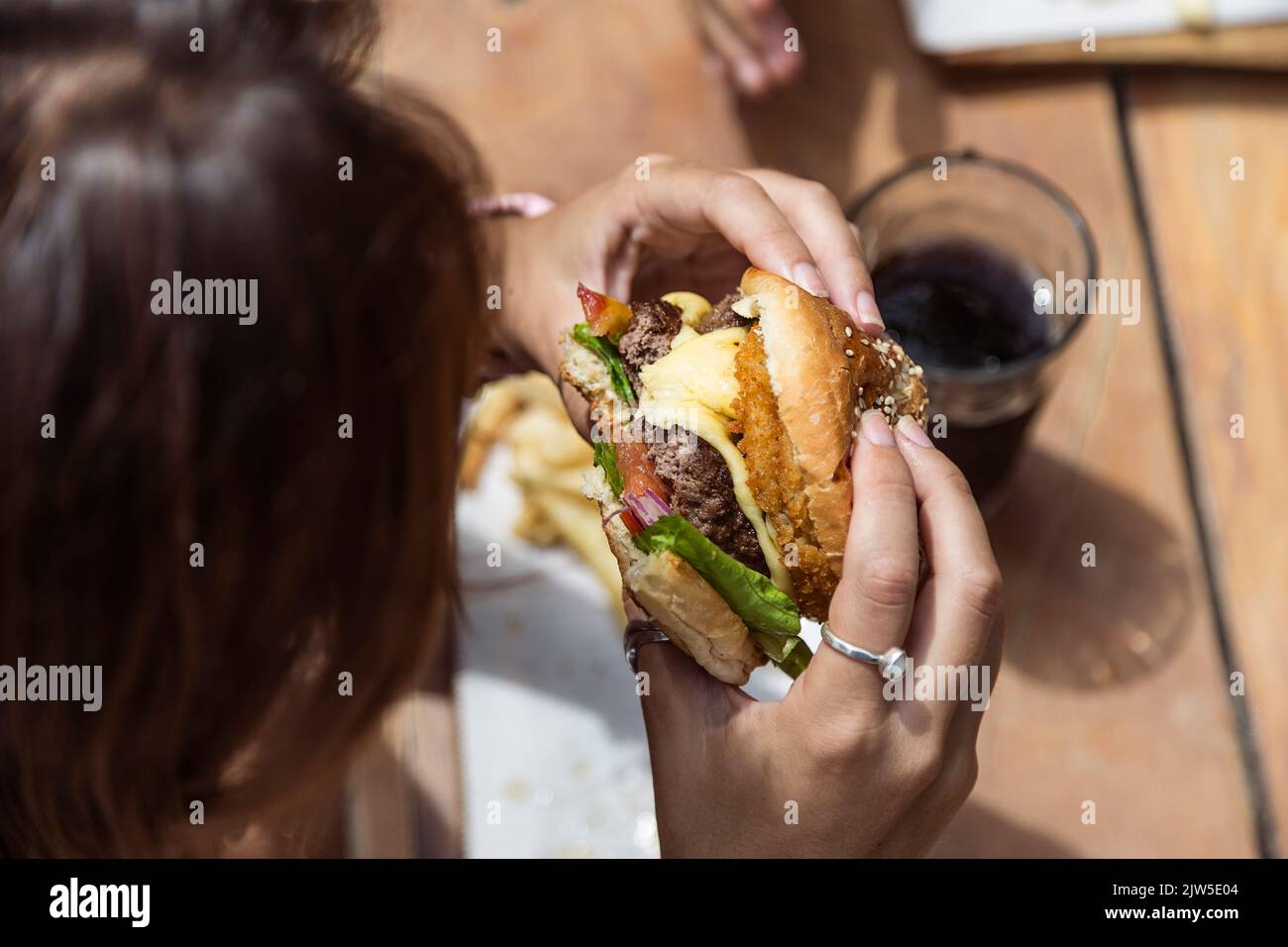 Hands holding a burger, on a restaurant table. Delicious and nutritious ...