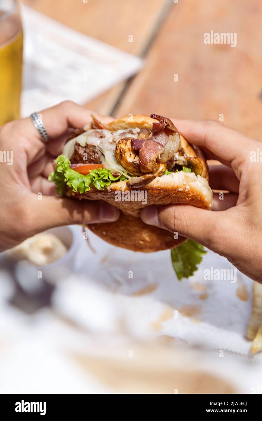 Hands holding a burger, on a restaurant table. Delicious and nutritious ...
