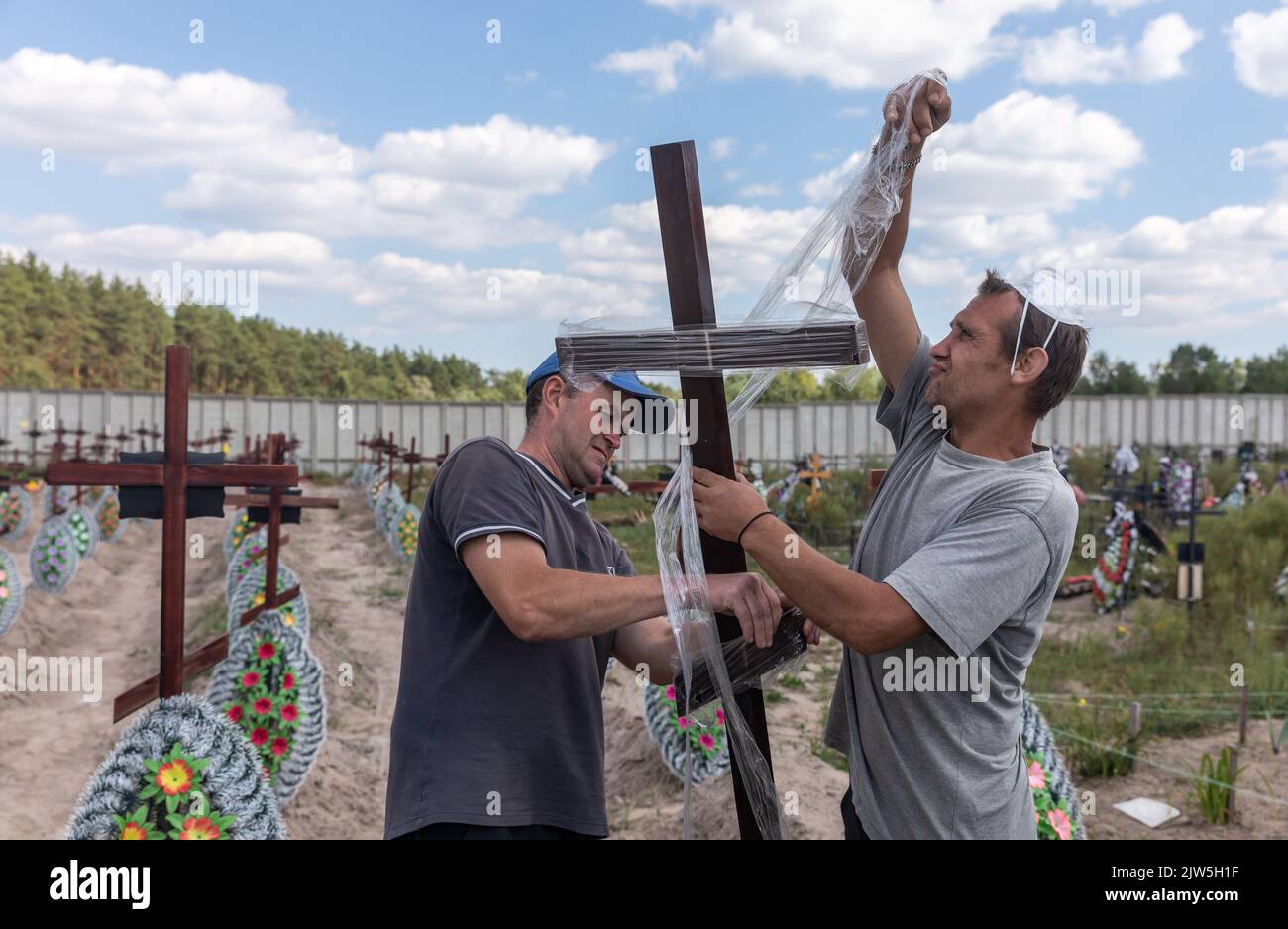 Local men put up crosses on the graves as they help during the funeral ...