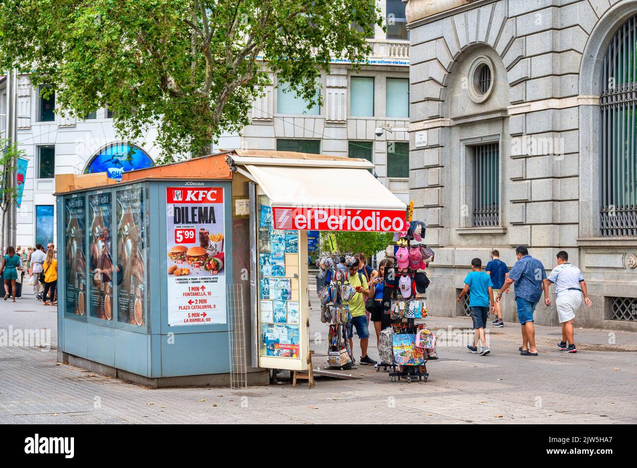 People walking in the city downtown where a kiosk reading El Periodico ...