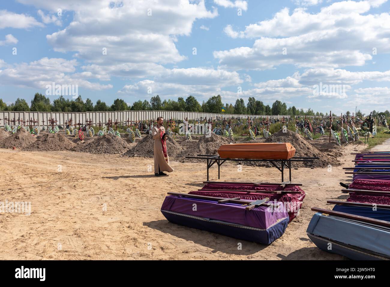 A priest reads a prayer and performs a funeral ceremony for the ...