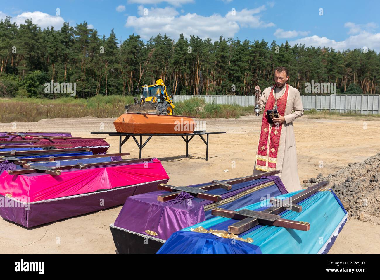 A priest reads a prayer and performs a funeral ceremony for the ...