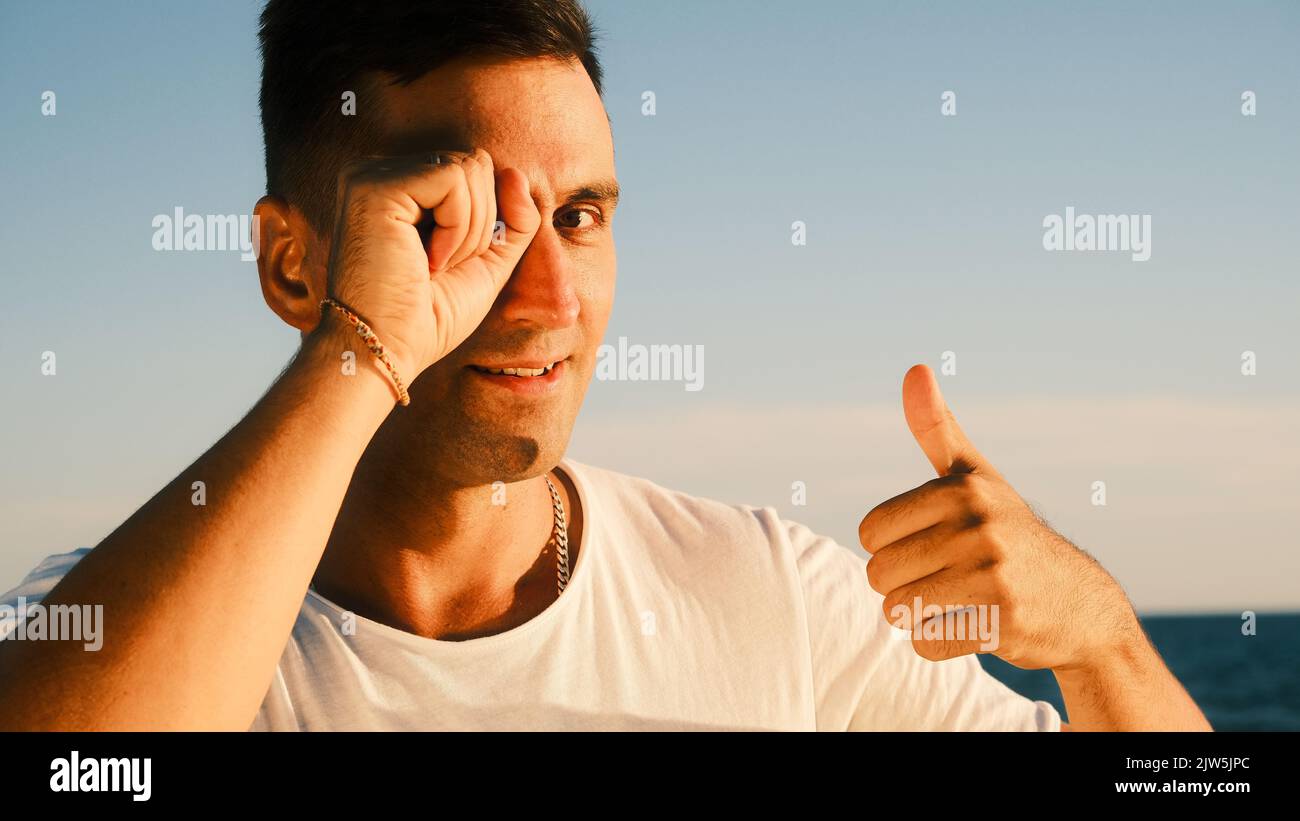 The young guy closed his right eye and raised the index finger of his ...