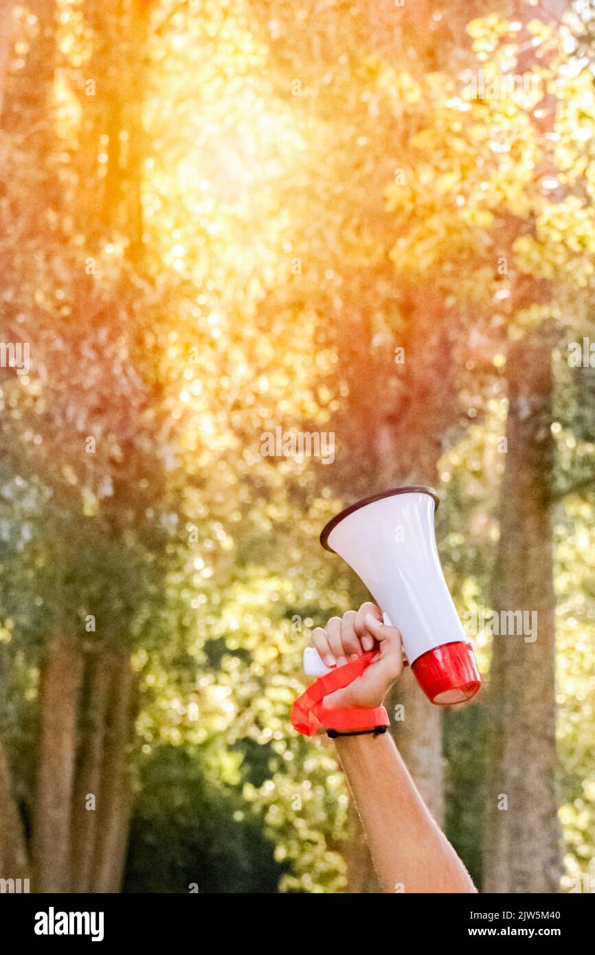megaphone with loudspeaker in hand in the middle of forest trees to ...