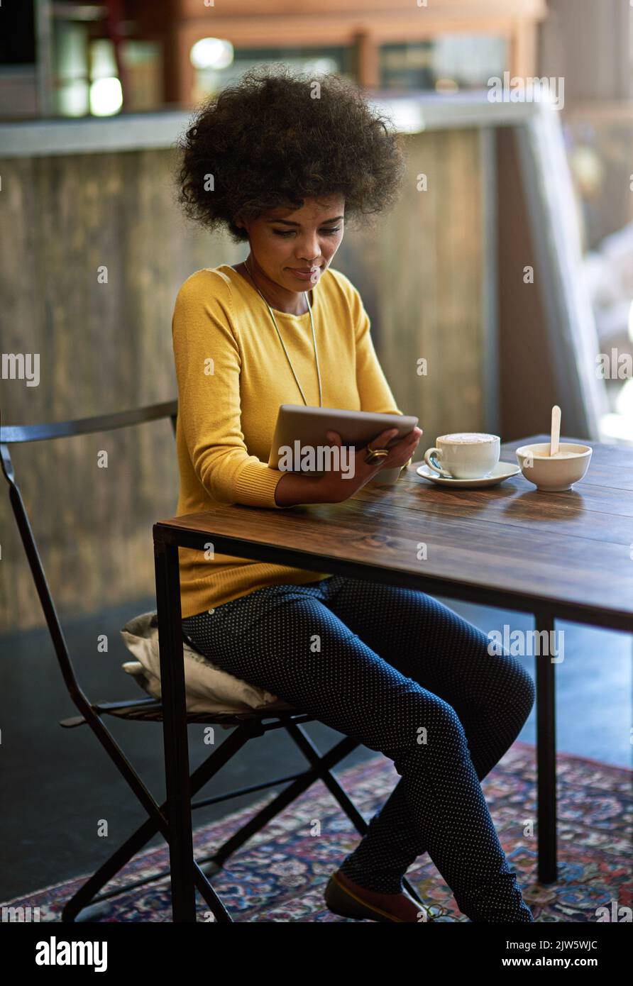 Staying connected in the cafe. a young woman using a digital tablet in ...