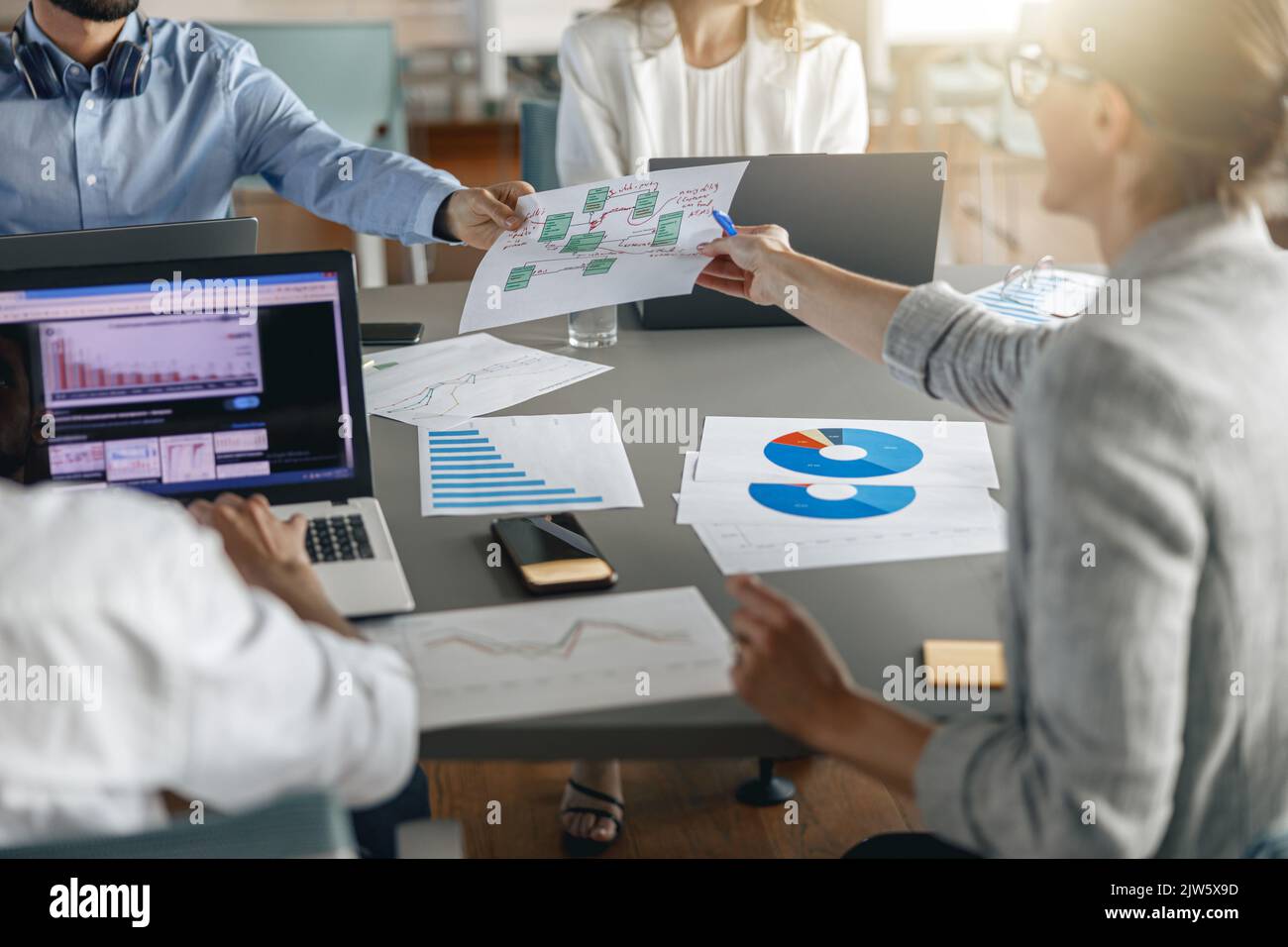 Group of busy coworkers working together analyzing the charts in modern ...