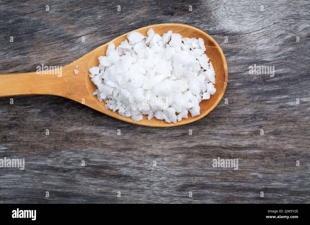Large sea salt in a spoon on a wooden background Stock Photo - Alamy