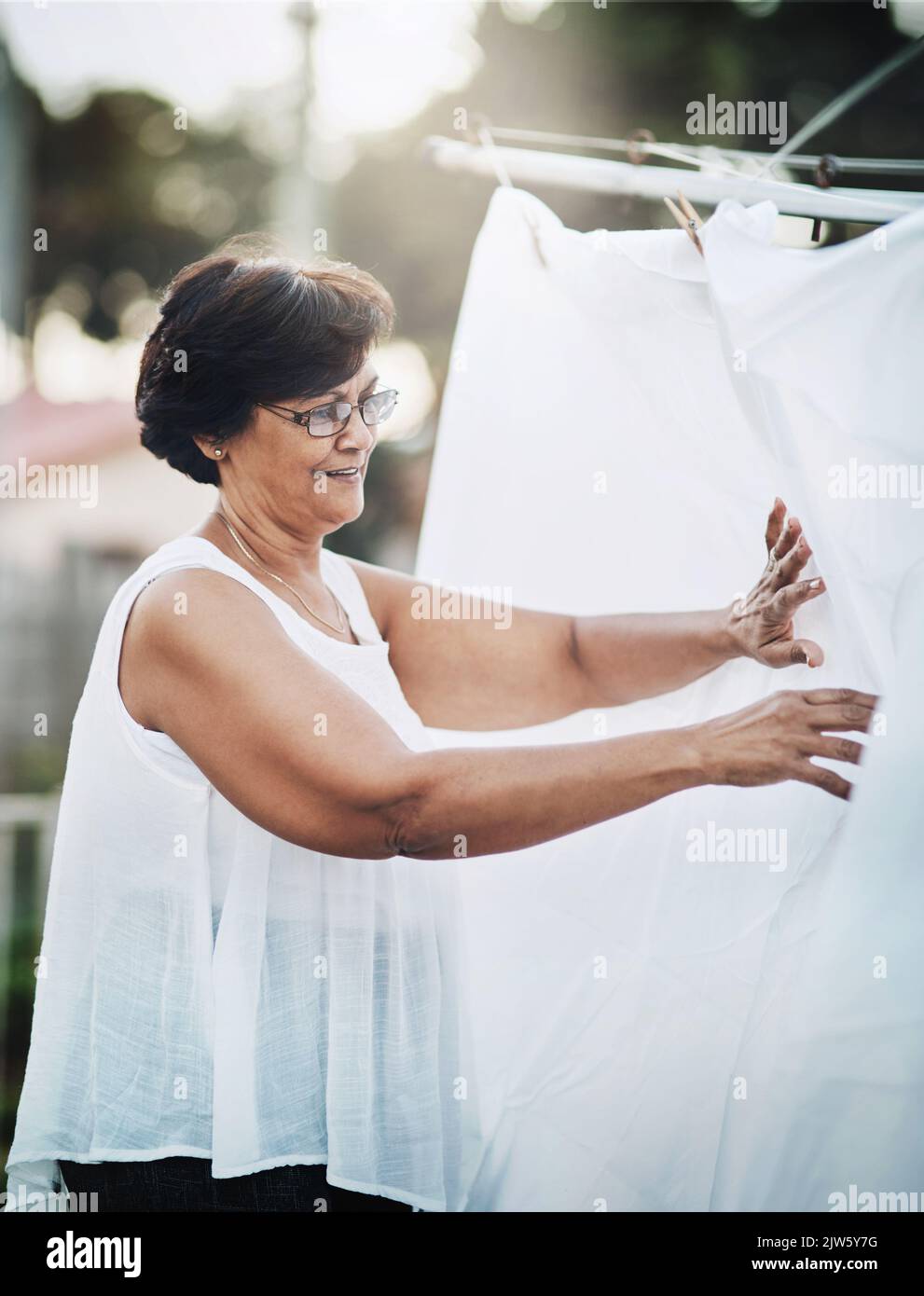 These will get dry in no time. a mature woman hanging up laundry on a ...