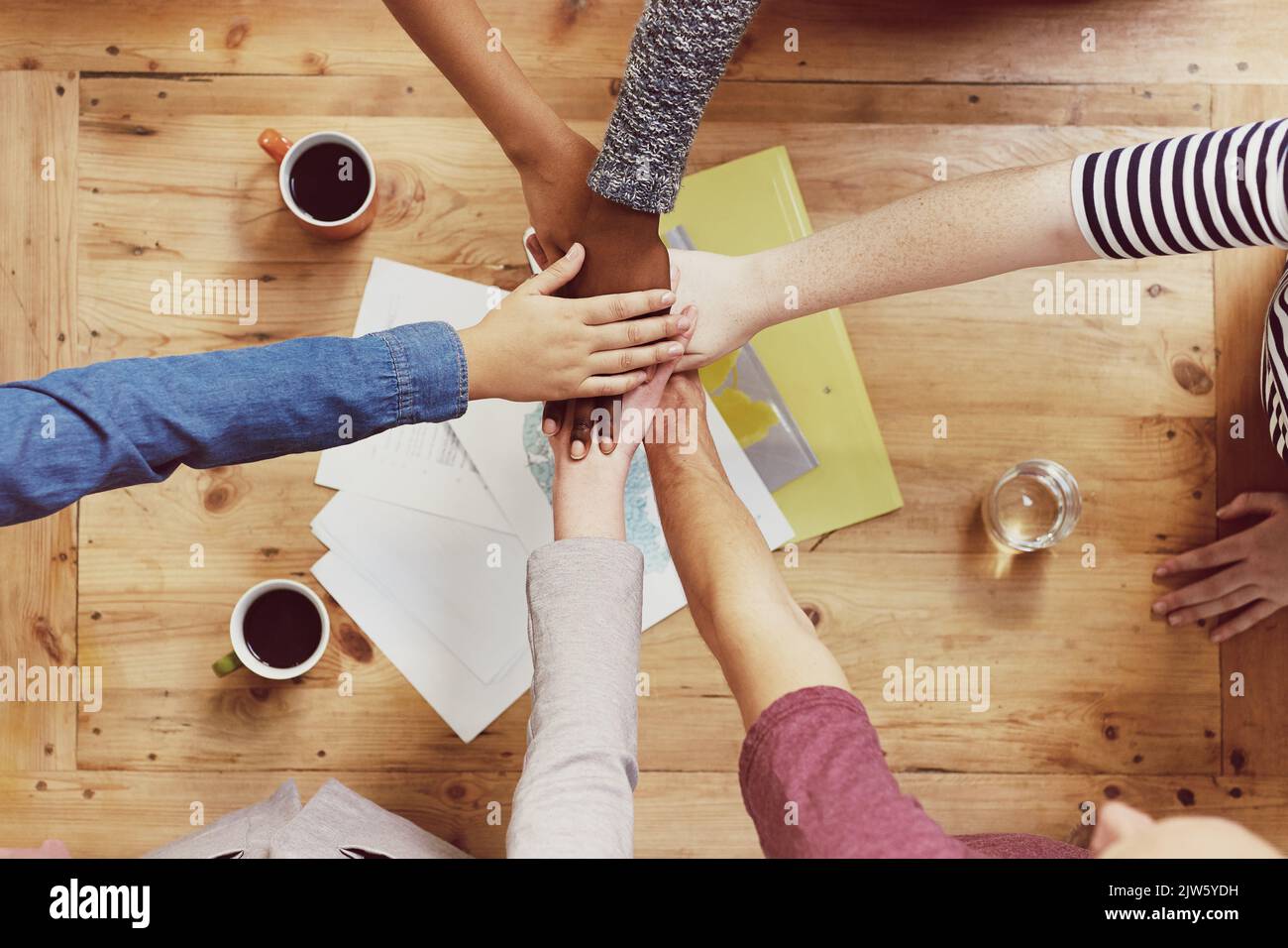 Lets accomplish this as a team. a group colleagues reaching their hands ...