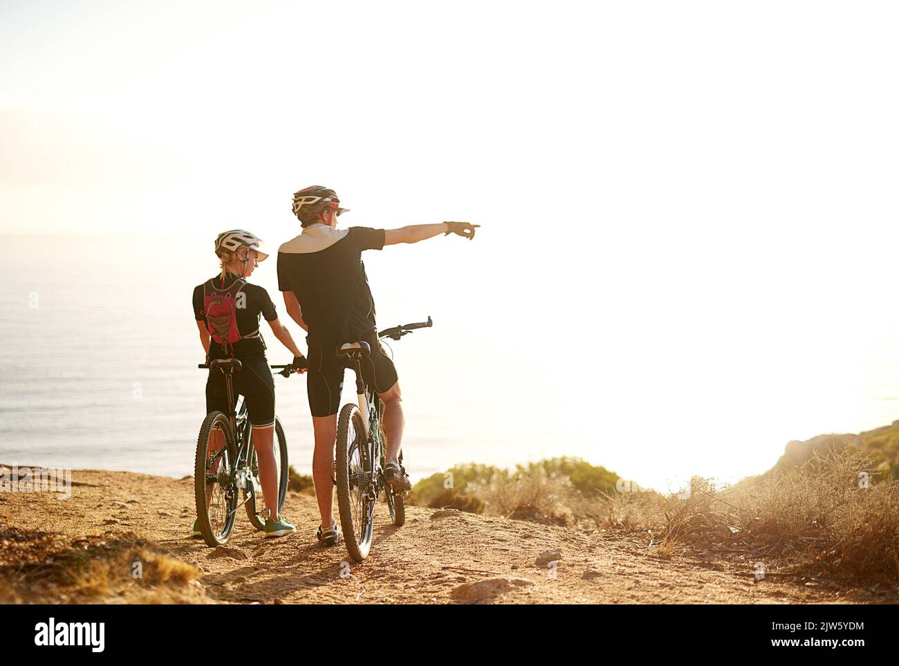 Biking is freedom. a young couple admiring the view from a hilltop ...