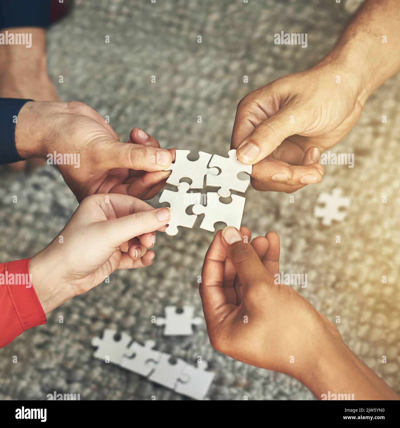 Putting it all together. High angle shot of four unrecognizable businesspeople building a jigsaw ...