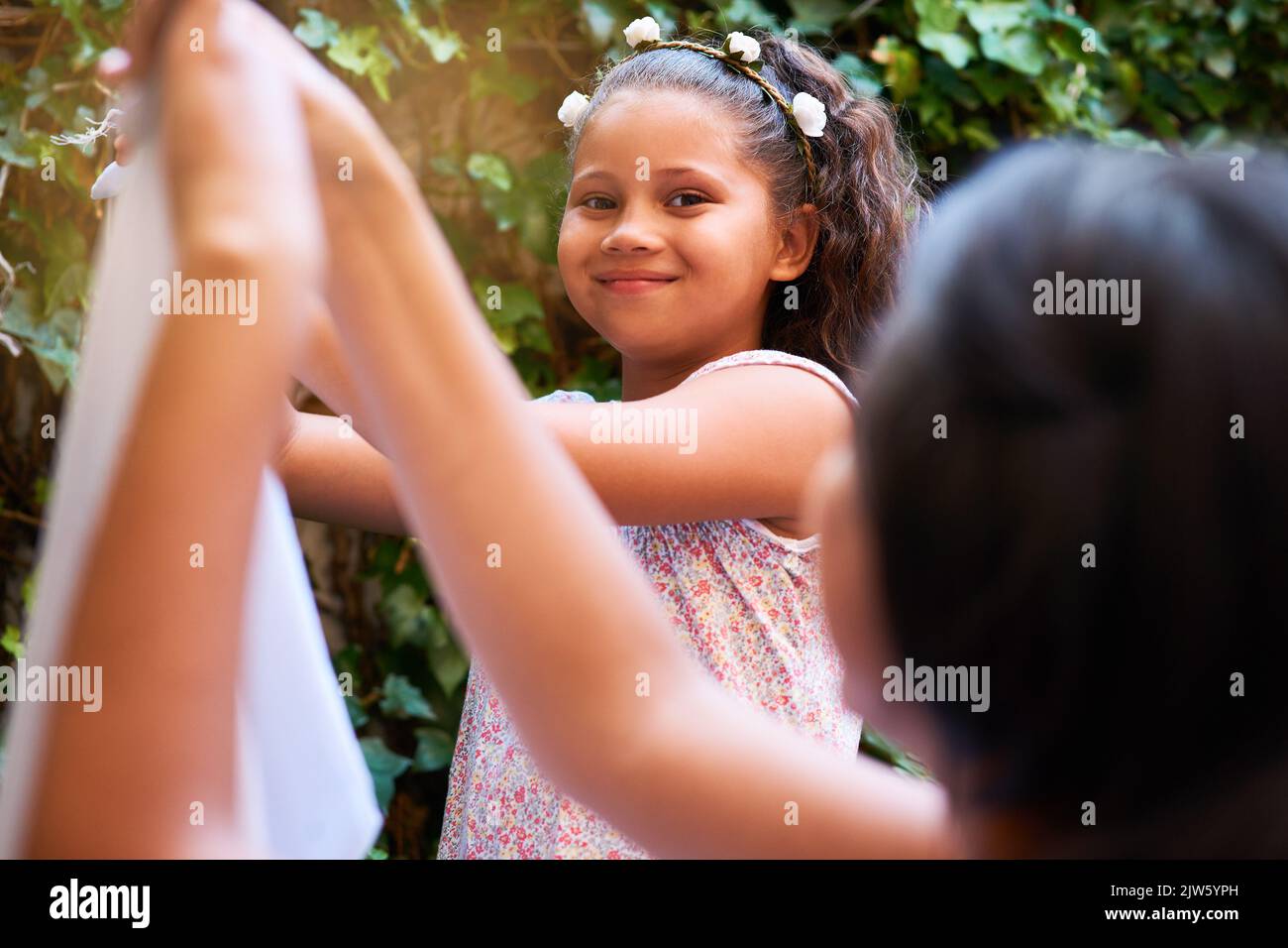 Im mommys best helper. Portrait of a young girl hanging up laundry on a washing line with her ...