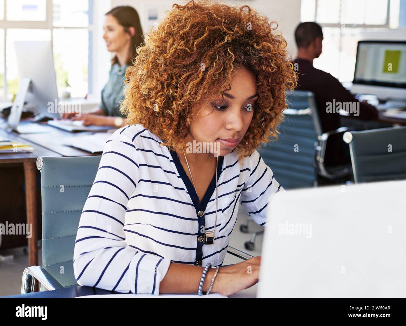 Fully engaged in her work tasks. a young woman using a computer at her ...