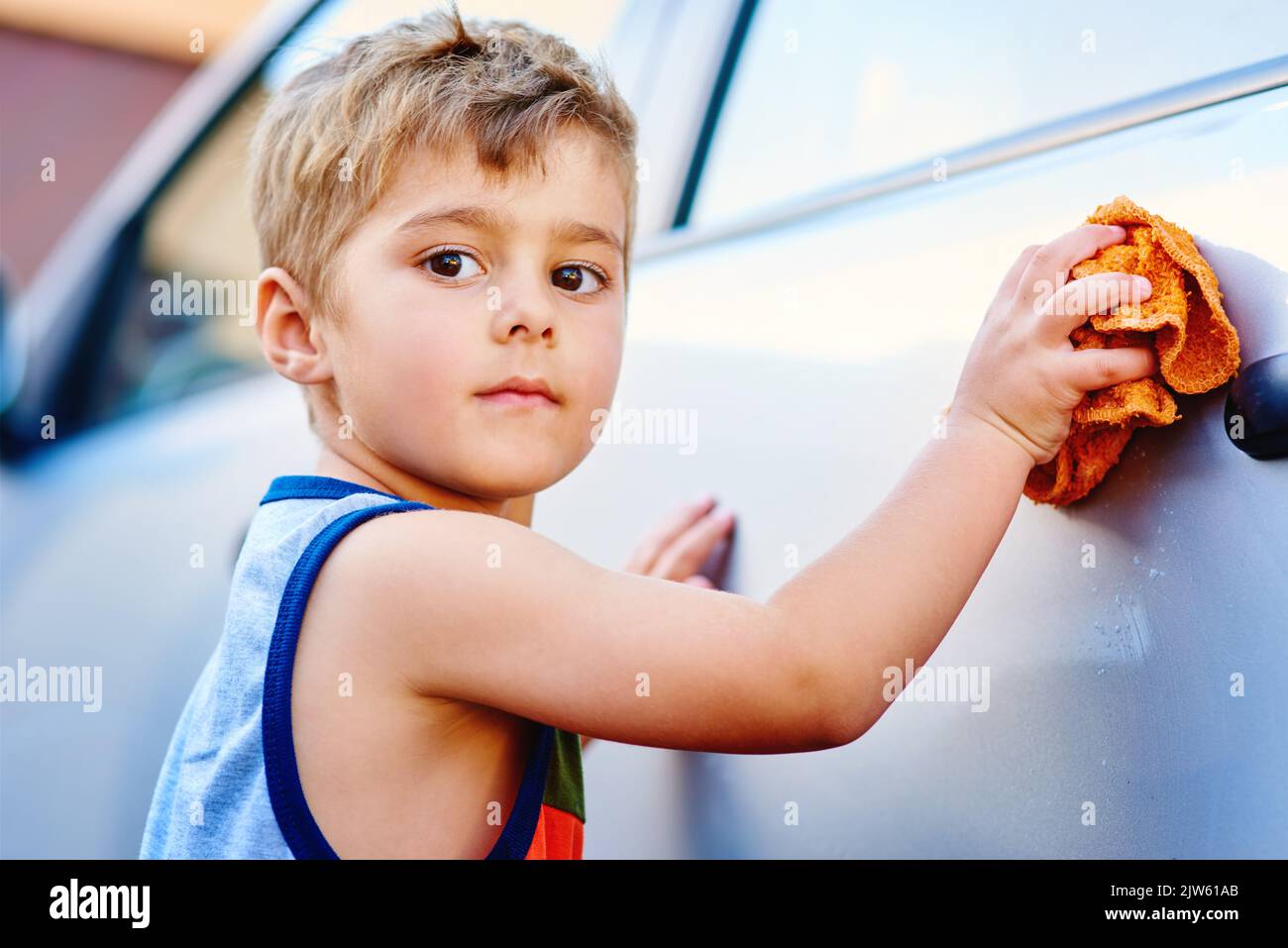 Getting it squeaky clean. an adorable little boy washing a car outside ...