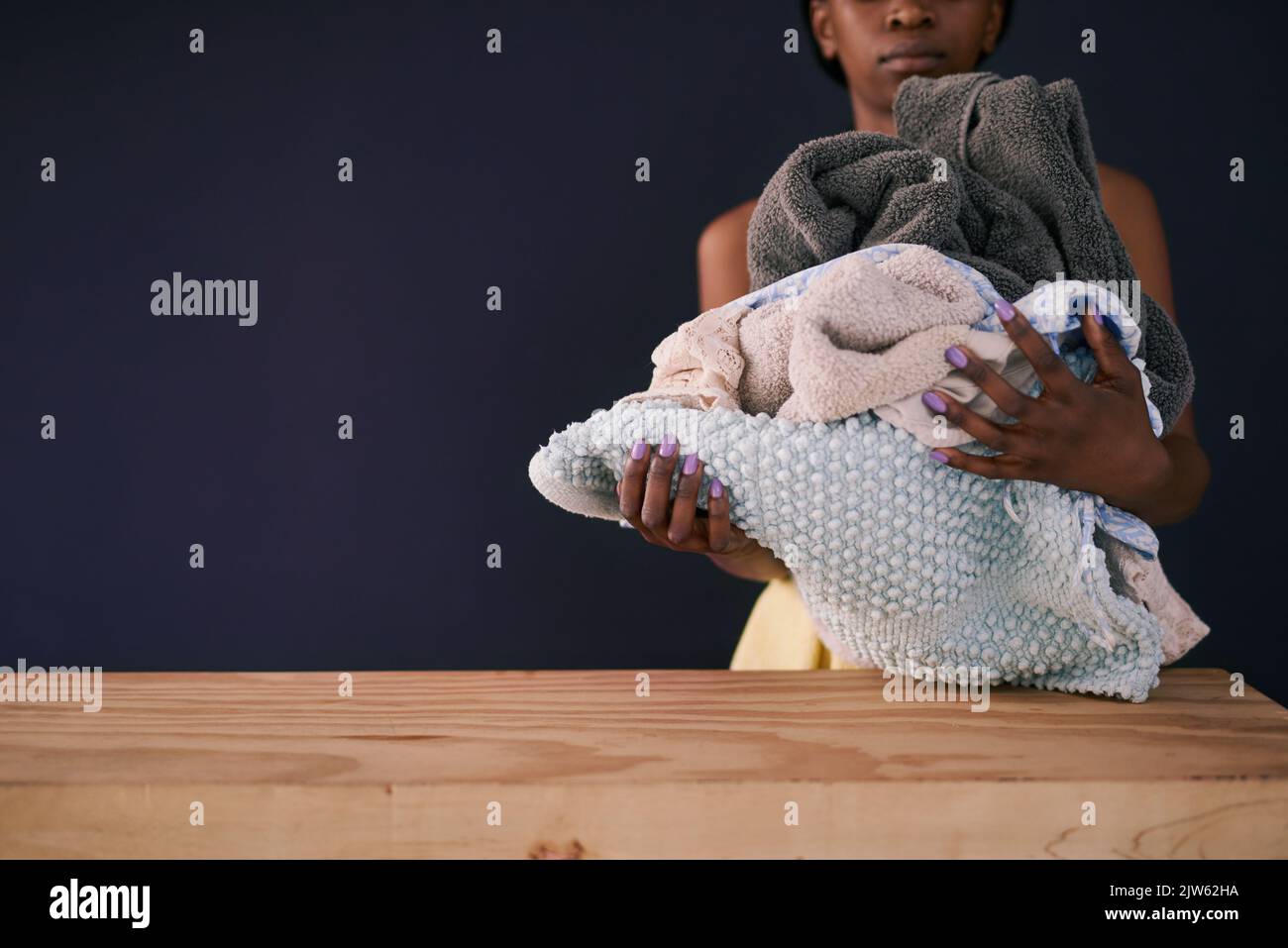 Tackling some laundry chores. a young woman carrying a pile of laundry ...