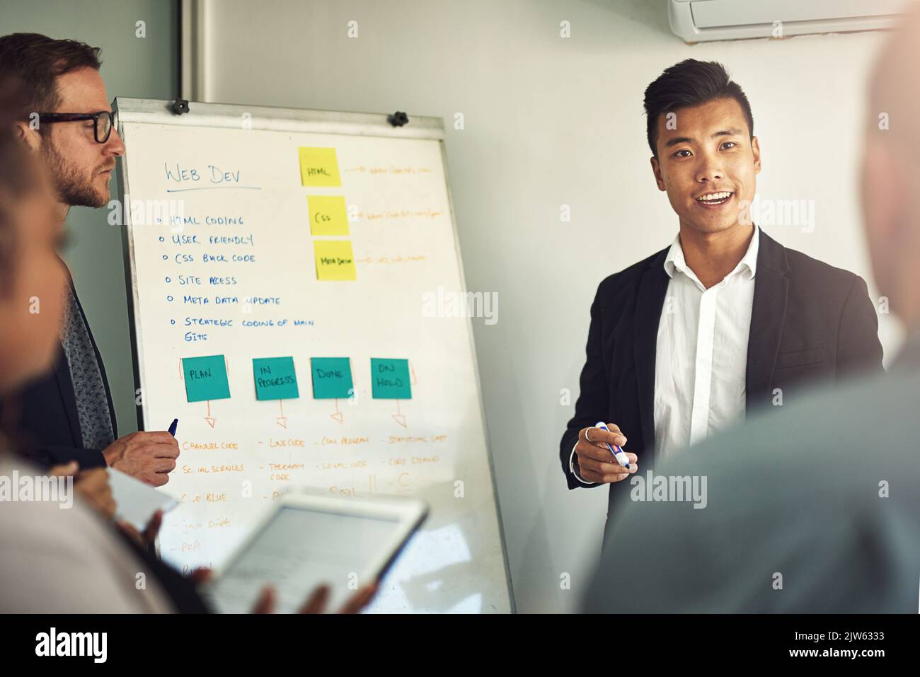 Improving his teams workflow. a young man giving a presentation to ...
