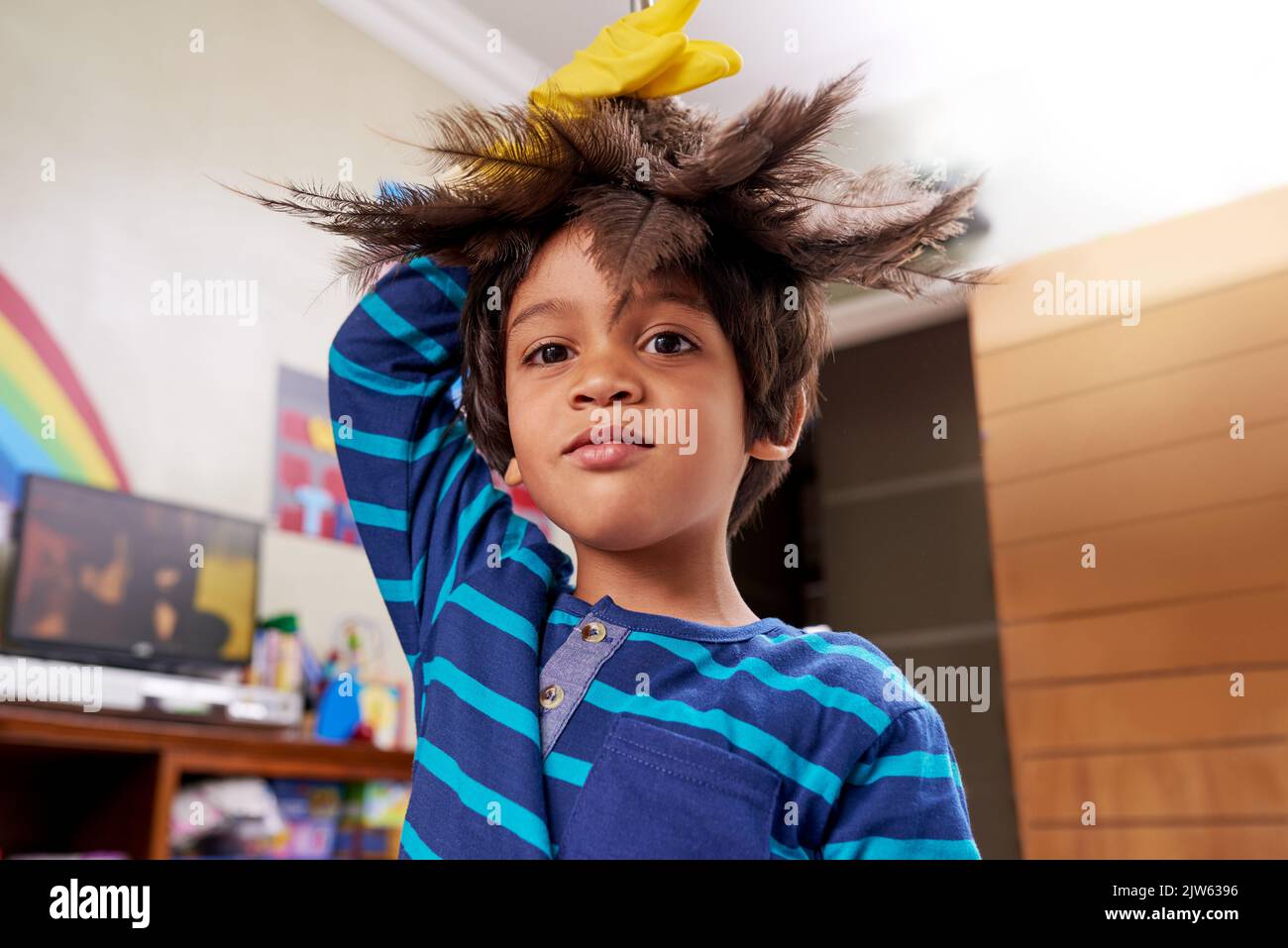Chores can be fun too. Portrait of a young boy holding a feather duster ...