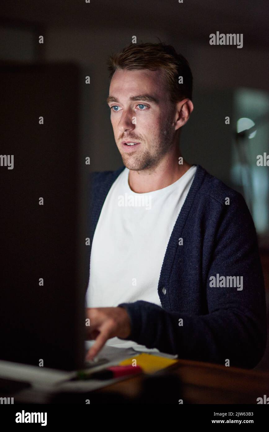 Focused on finishing before the morning. a young man working late in ...