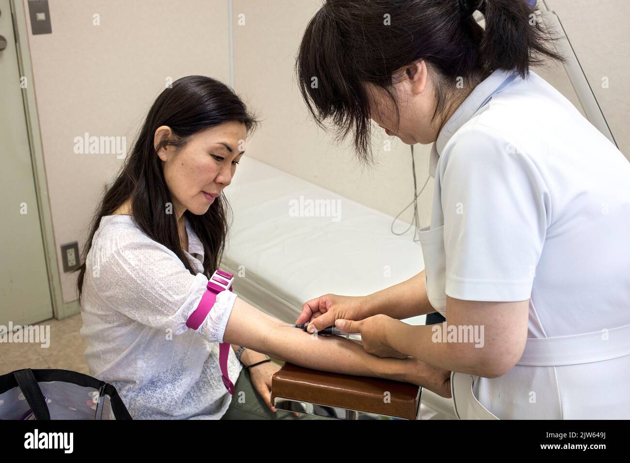 Nurse uses needle on patients arm for blood draw at medical clinic, Ota ...