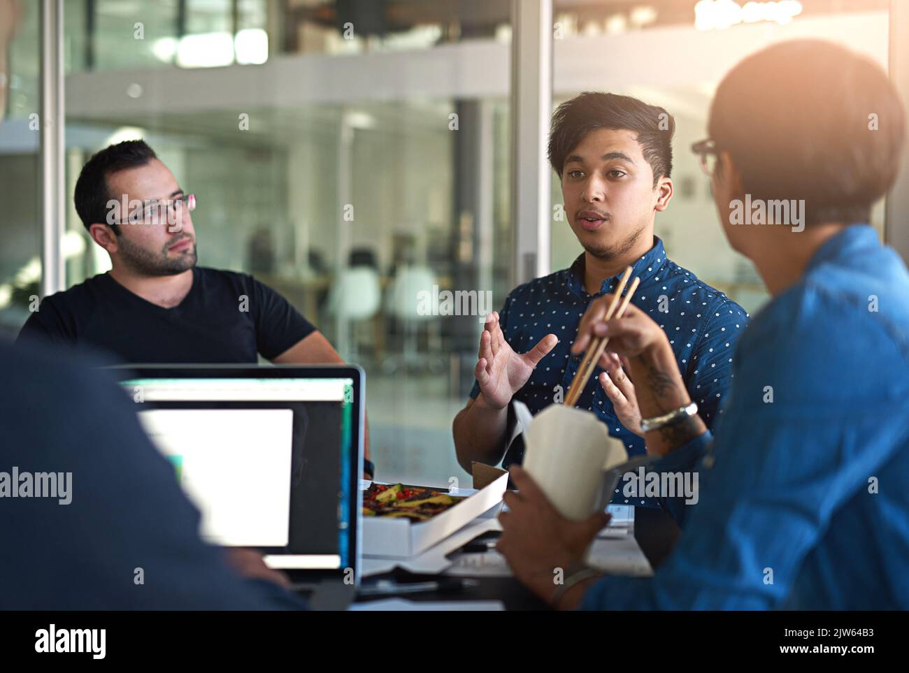 Putting his idea forward. a group of colleagues eating while having a ...