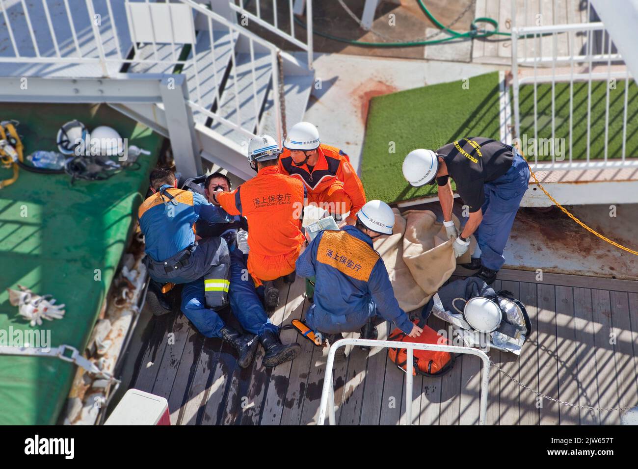 Paramedics giving oxygen to rescued worker on ship in Tokyo; Japan ...