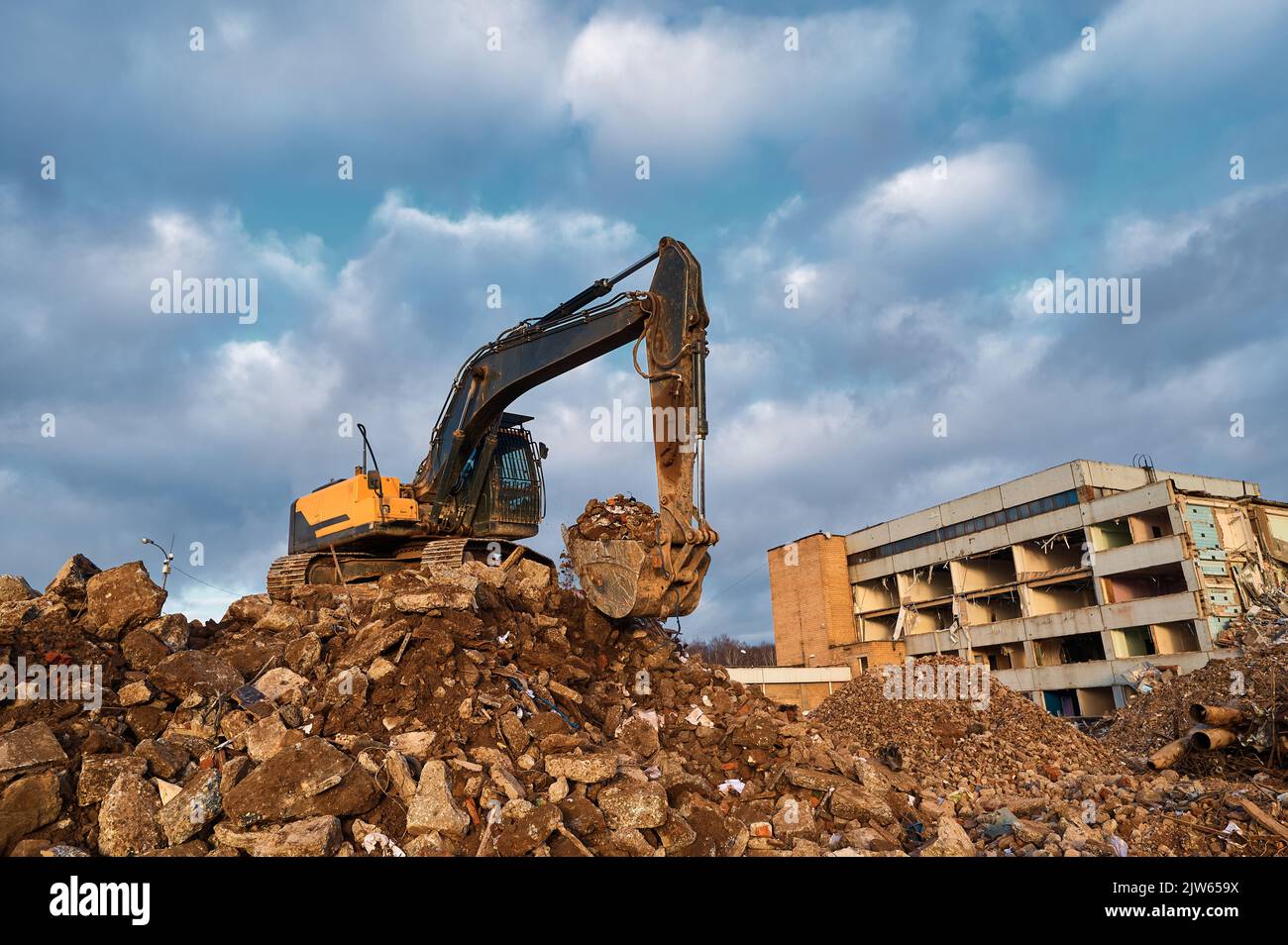 Bucket of excavator digs leftovers of destroyed building Stock Photo ...