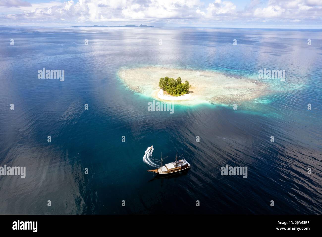 Aerial view a small coral island with Coralia live-aboard boat, Raja ...