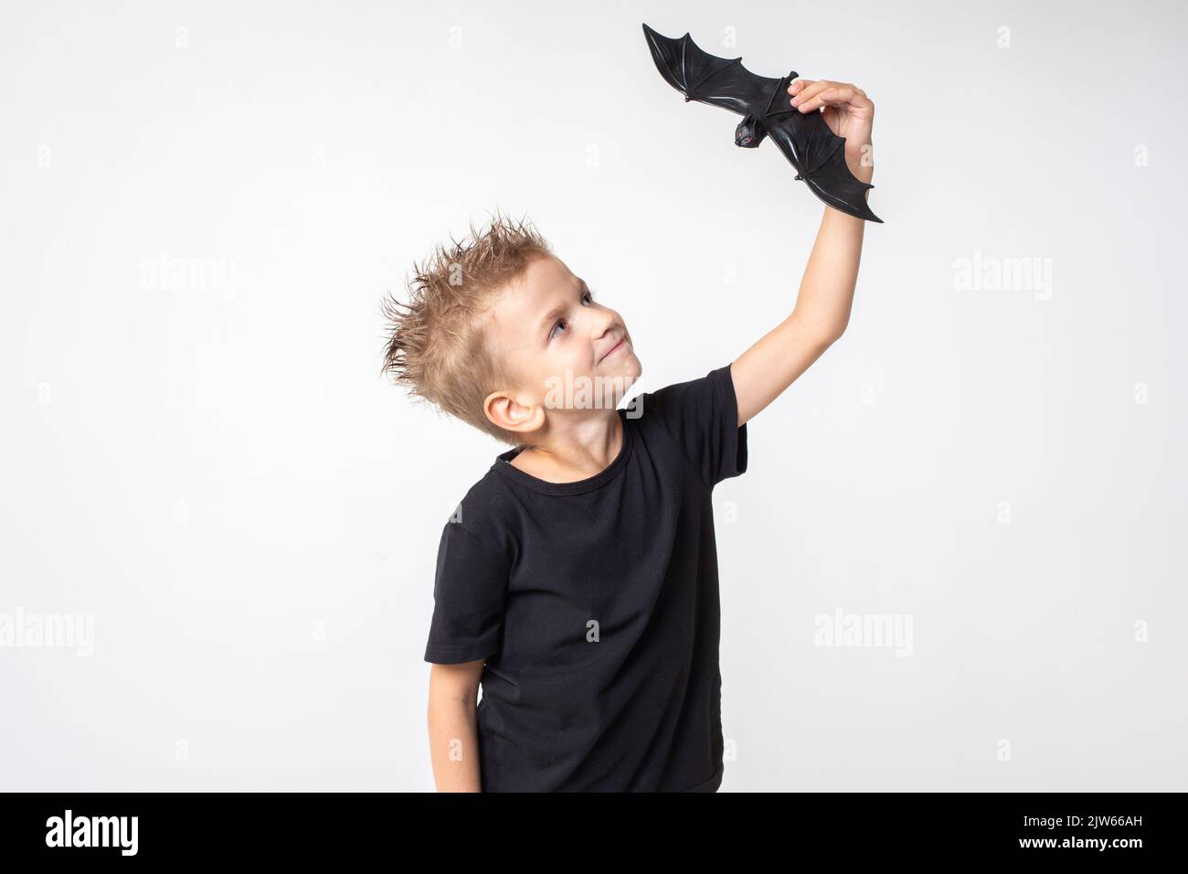 Kids Halloween. A beautiful emotional boy in a black T-shirt holds a ...