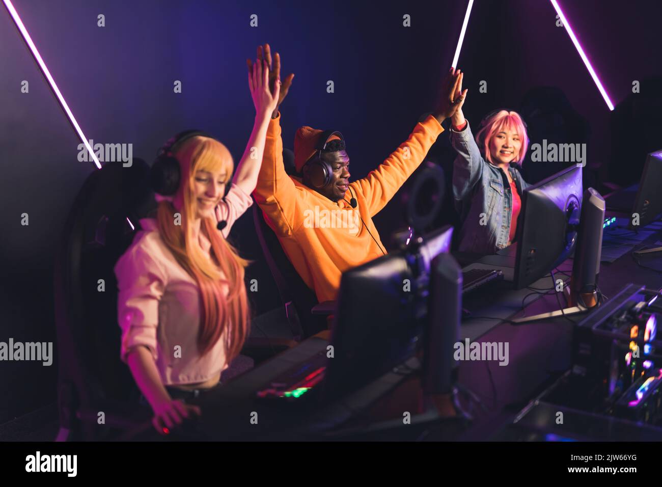 Three teenagers wearing colorful clothes and headsets celebrating ...