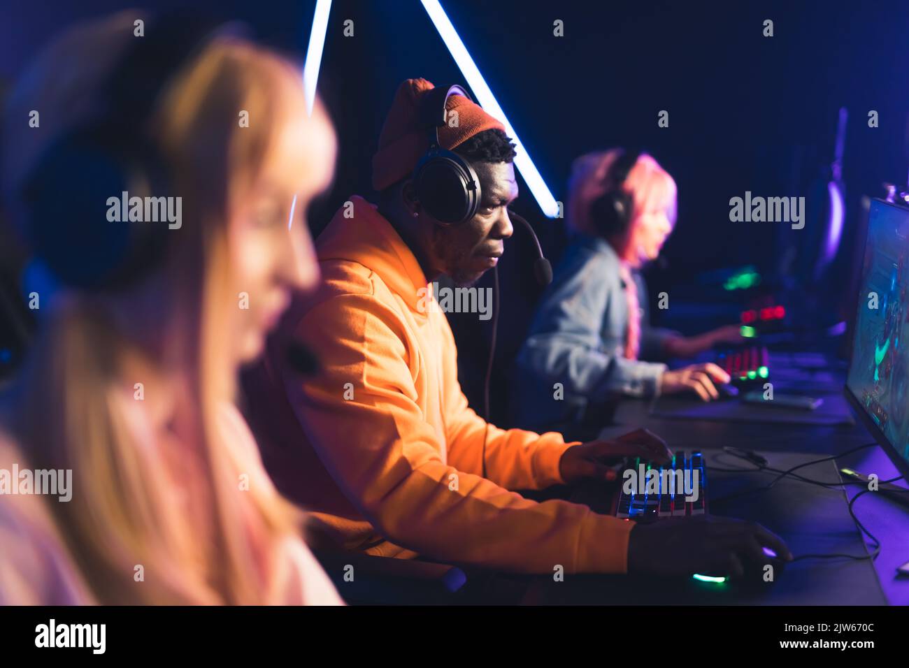 Three teenagers wearing colorful clothes focused on playing online game ...