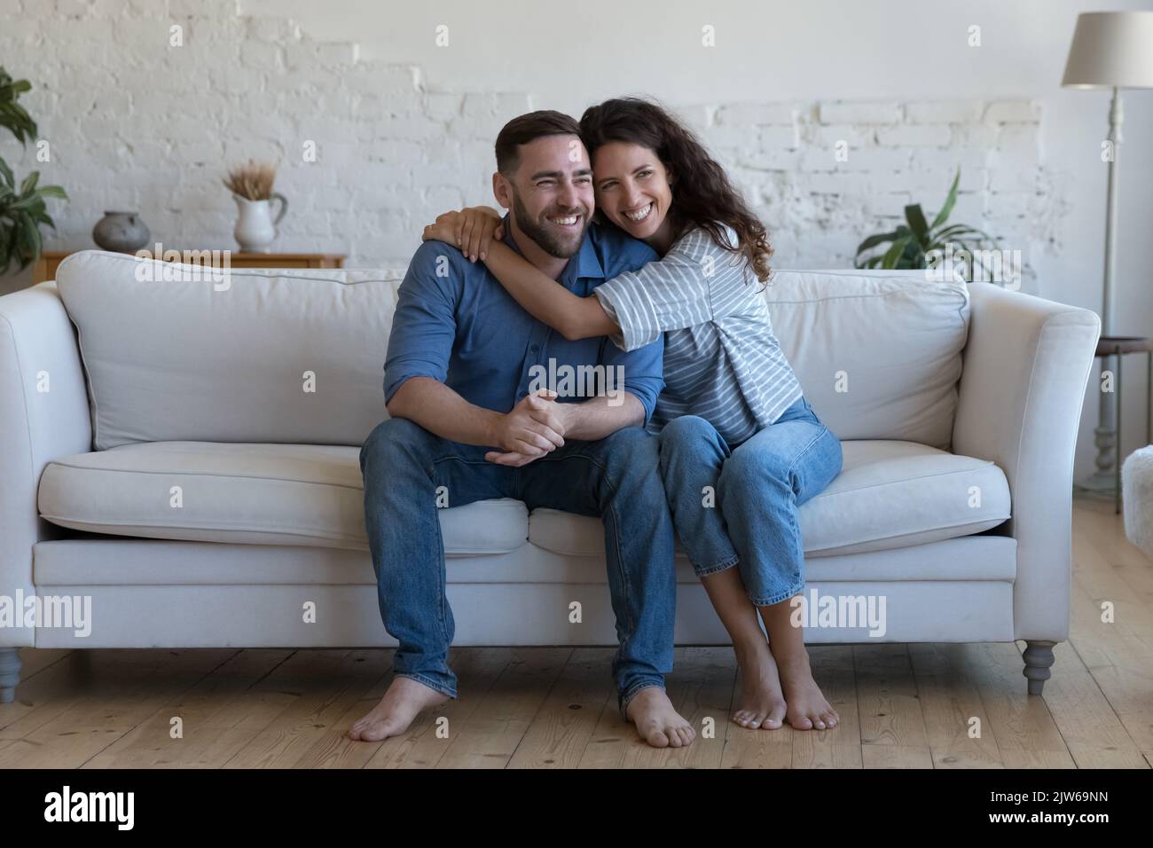 Romantic couple hugging seated on sofa at home Stock Photo - Alamy