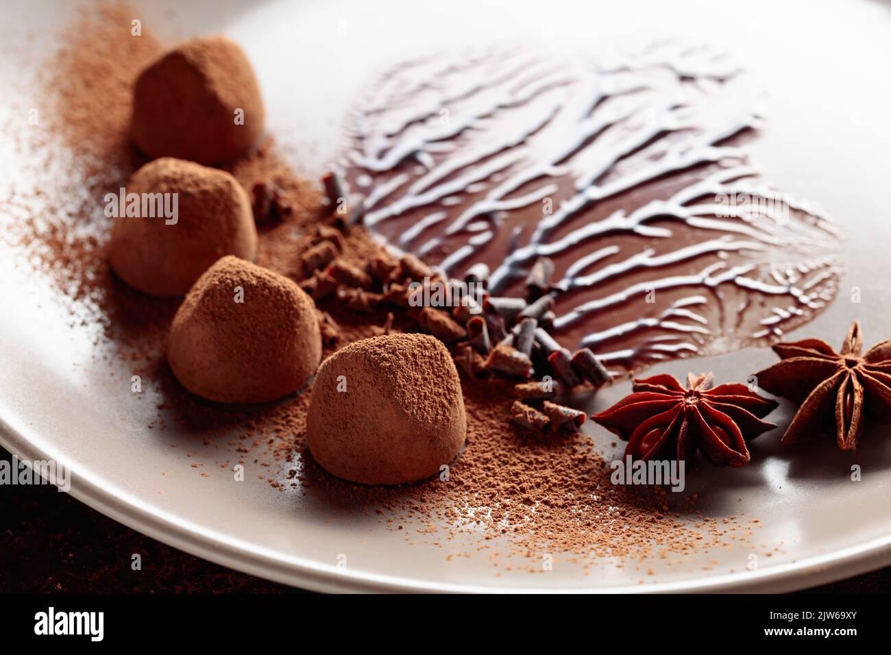 Chocolate truffles on a beige plate with chocolate sauce. Sweets are ...