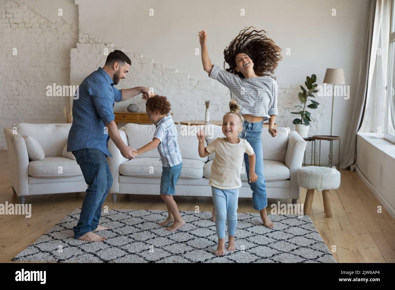 Cheerful couple with kids having fun dance in living room Stock Photo ...
