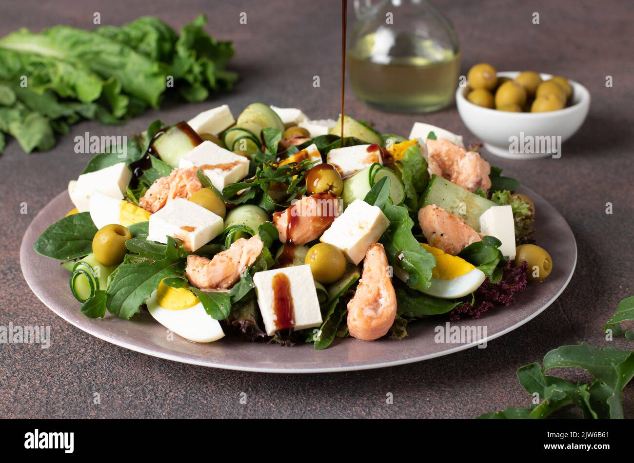 Salad with canned salmon, egg, cucumber, arugula and feta cheese poured ...