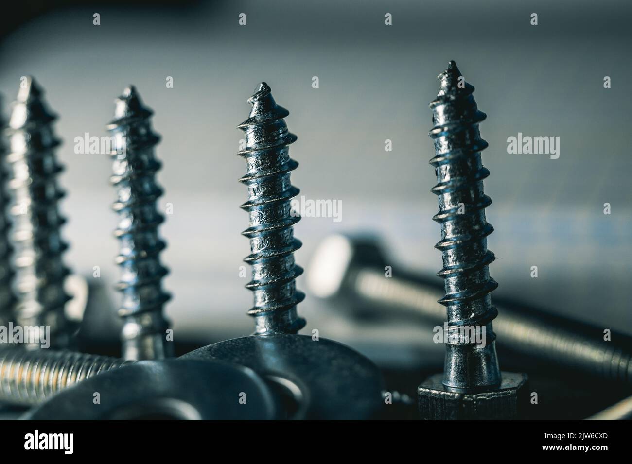 A closeup shot of metallic screws with a blur background of a graph ...