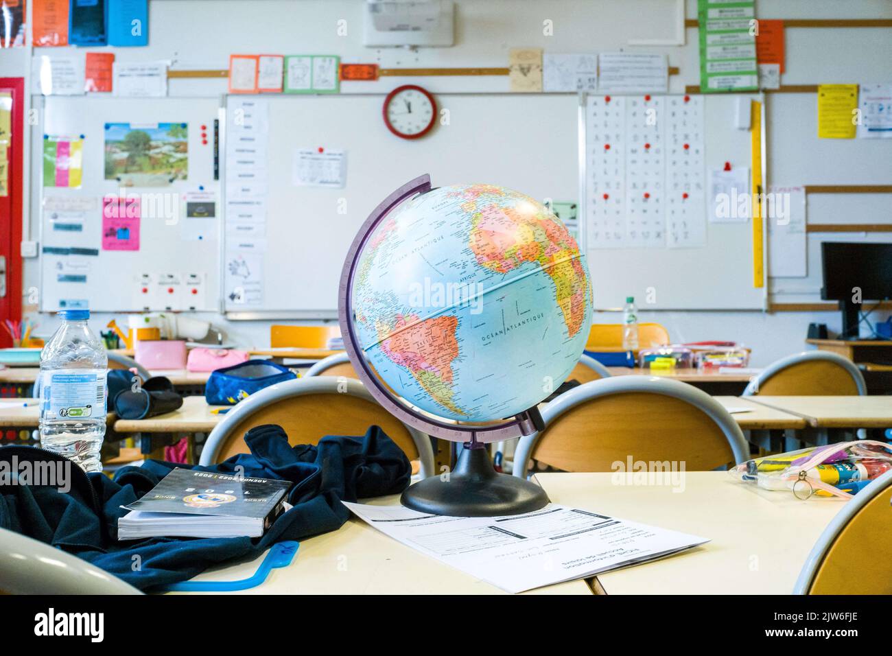 A globe on a classroom table without students, with the whiteboard in ...